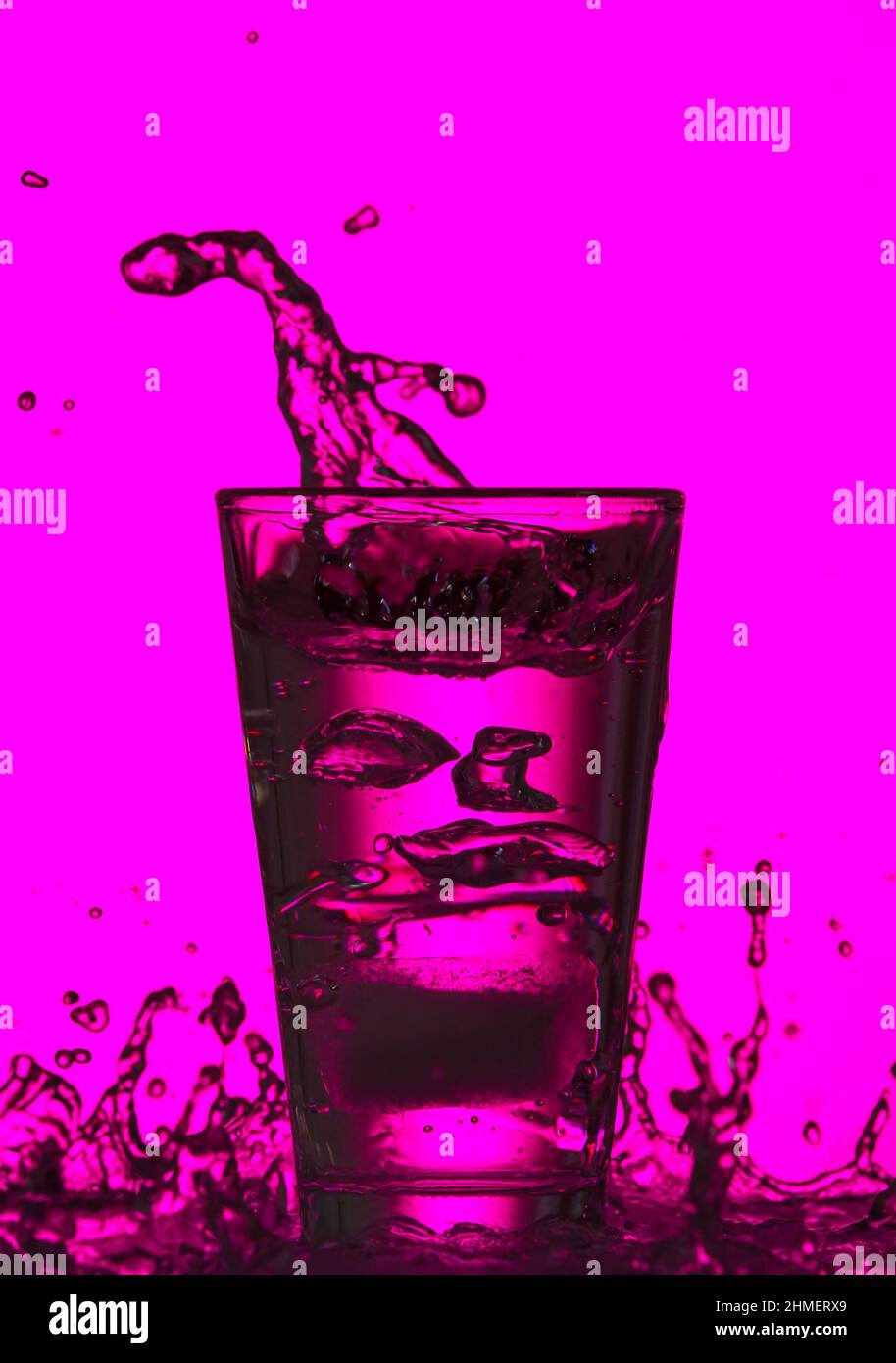 Glass of clear water with splash on color background Stock Photo - Alamy