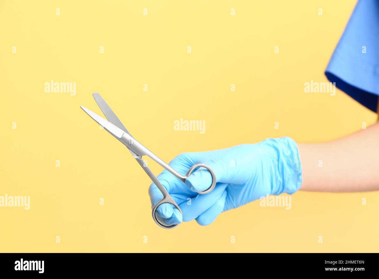 Female doctor with medical scissors on yellow background Stock Photo ...