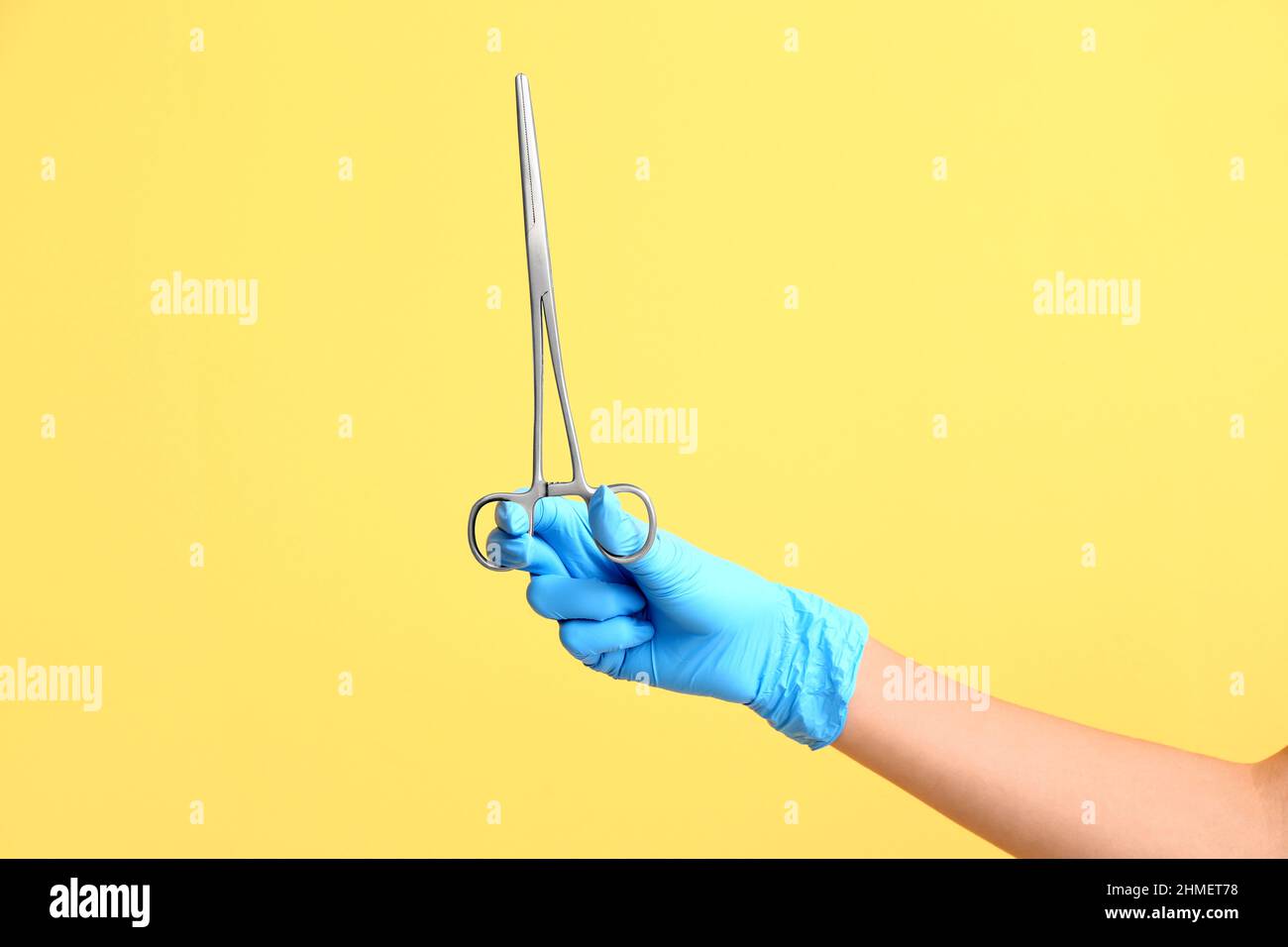 Female doctor with medical scissors on yellow background Stock Photo ...