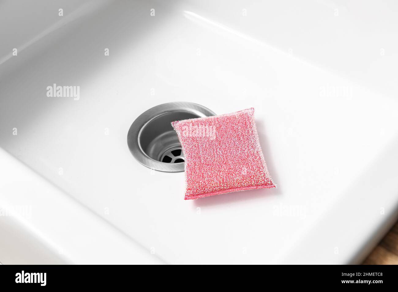 Pink cleaning sponge in ceramic sink, closeup Stock Photo - Alamy