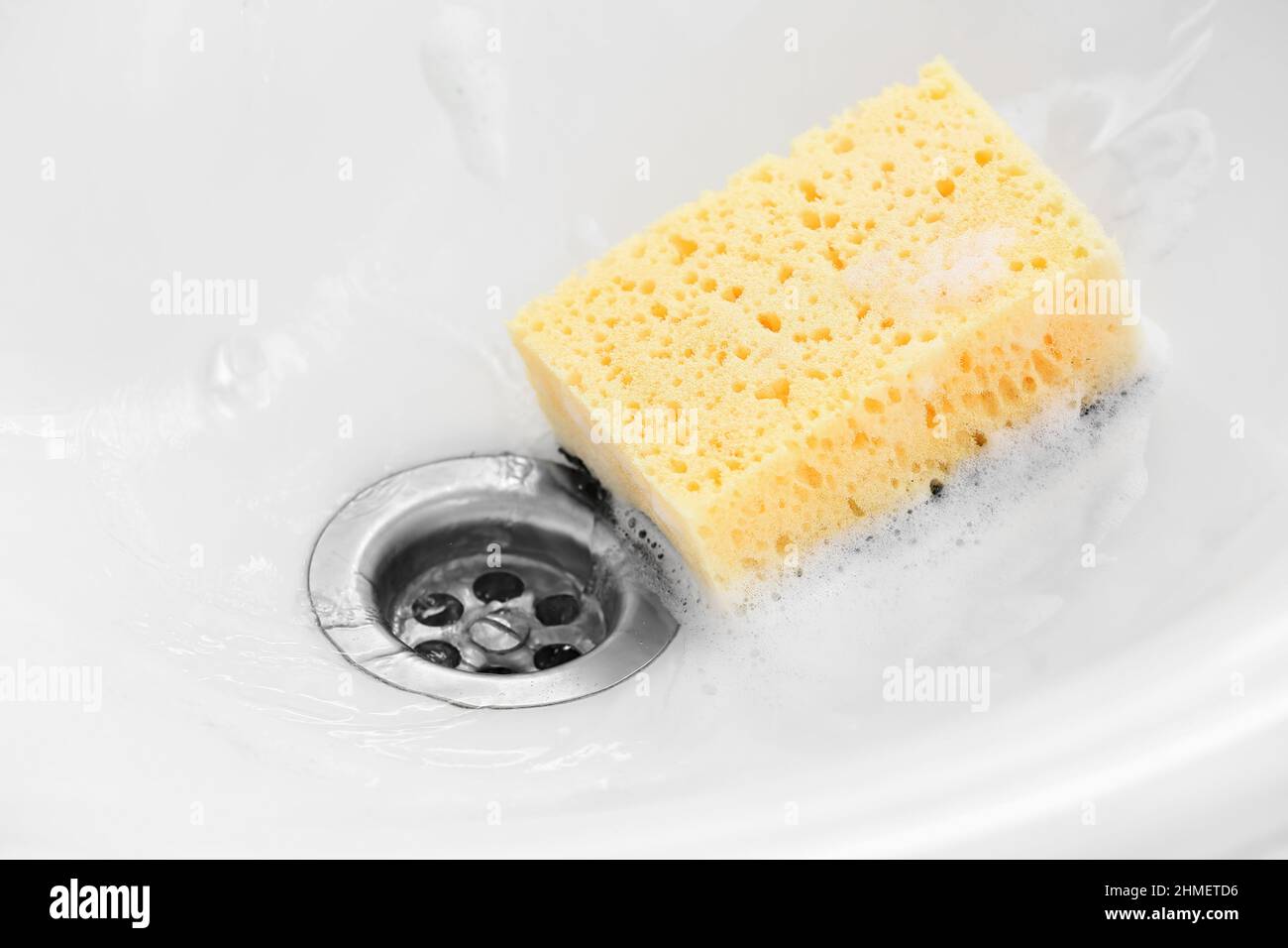 Yellow cleaning sponge with foam in ceramic sink, closeup Stock Photo ...