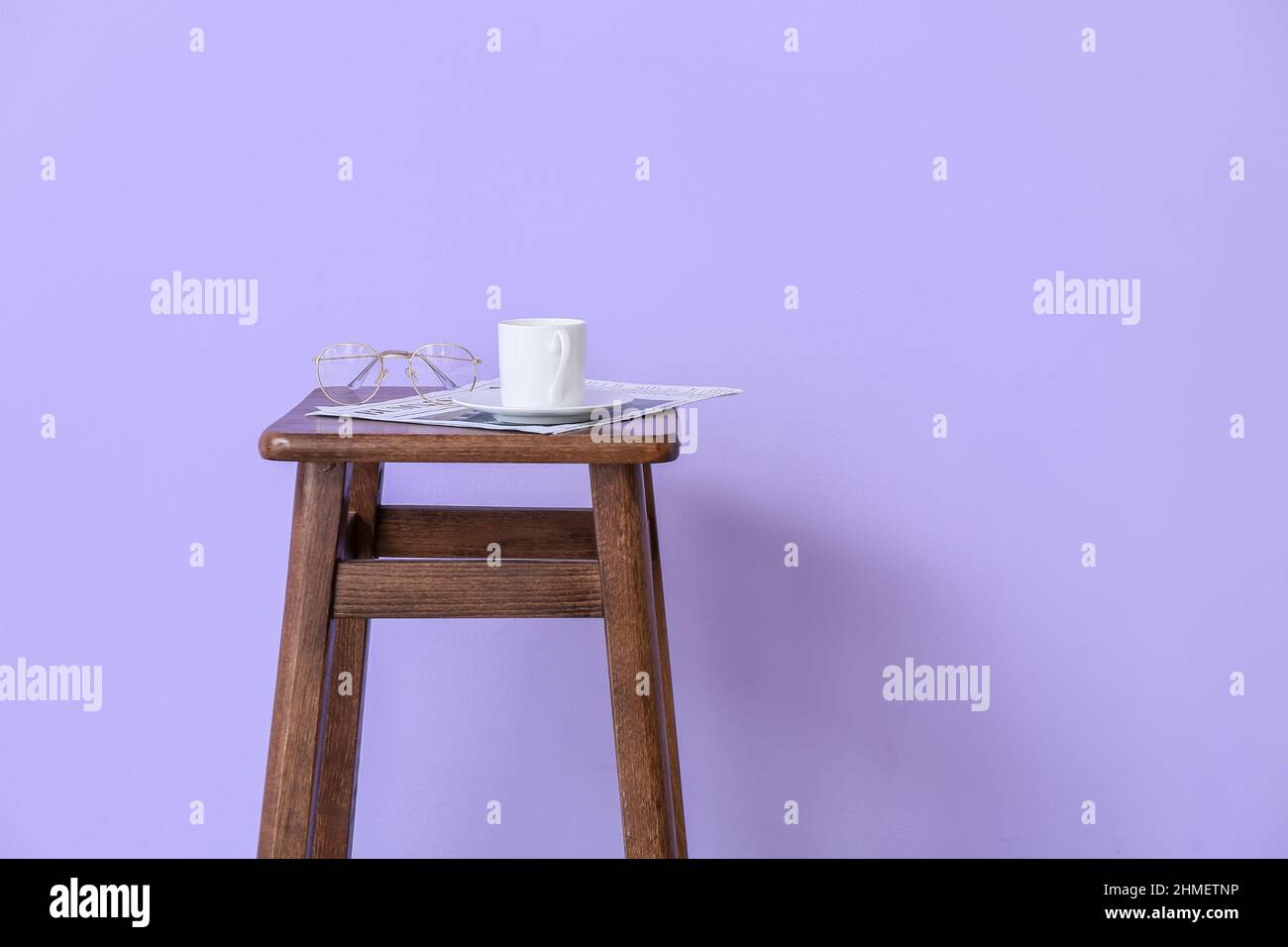 Wooden bar stool with cup of coffee, eyeglasses and newspaper near ...