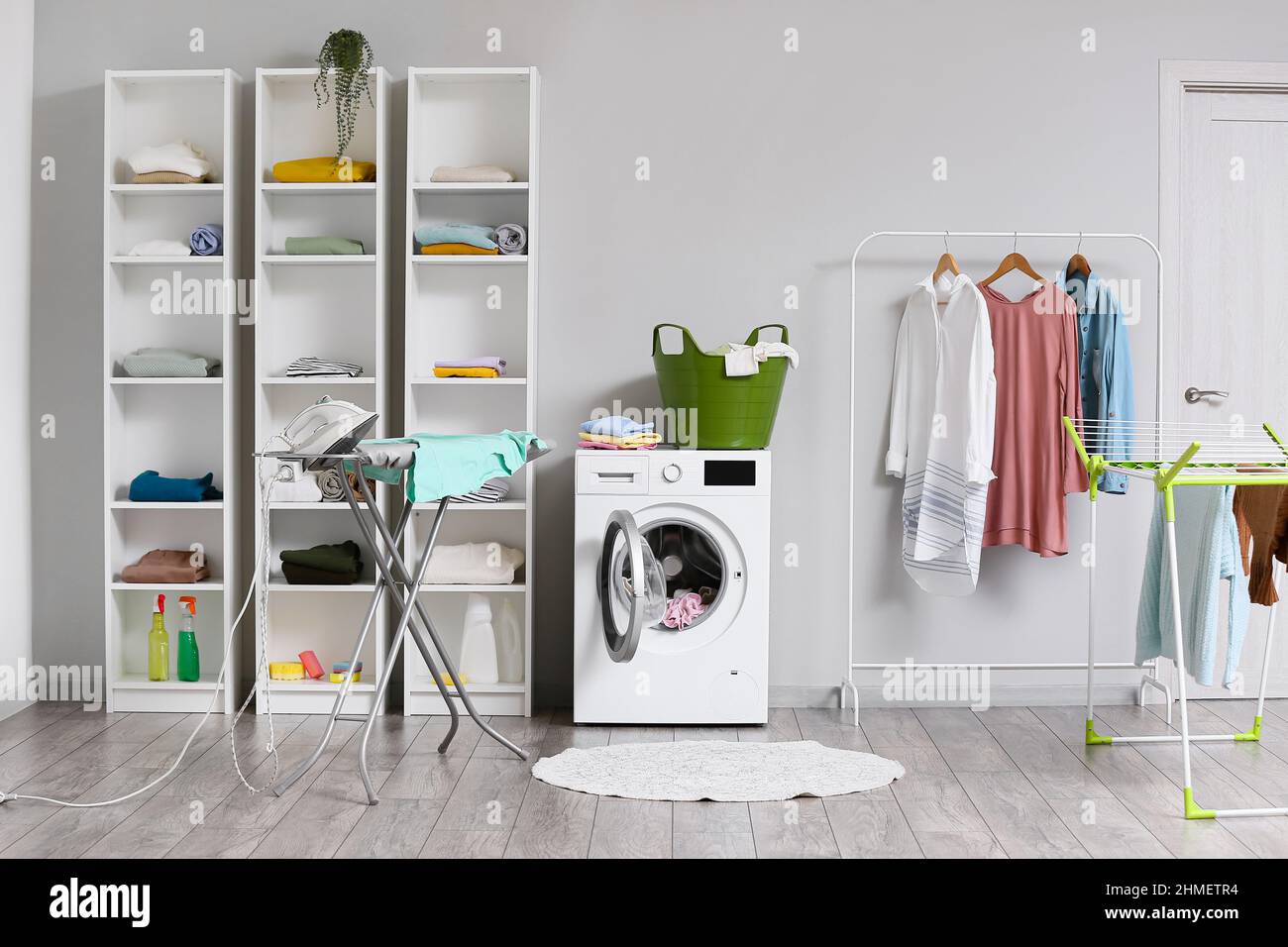 Interior of light laundry room with shelf units, washing machine and ...