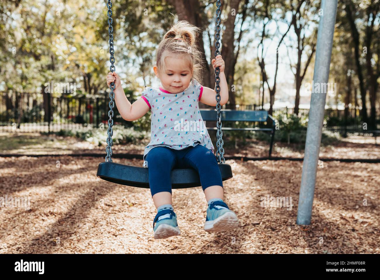 Child on a swing. Child playing on outdoor playground. Happy beautiful little girl having fun on ...