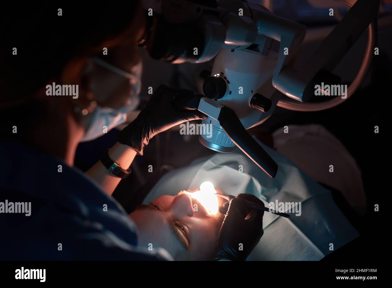 The dentist treats his patient's teeth with a microscope. The dentist ...