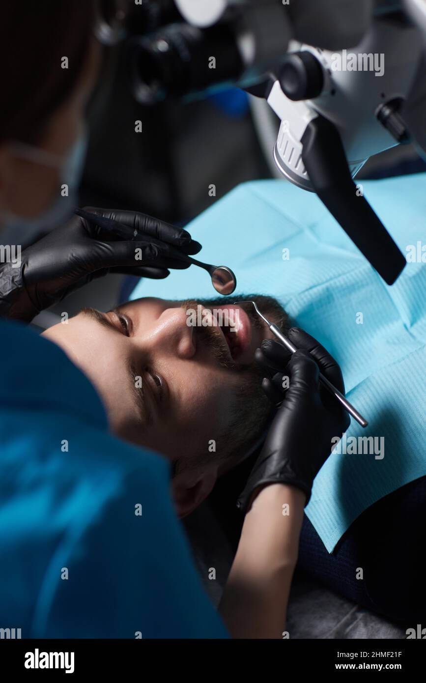 The dentist treats his patient's teeth with a microscope. The dentist ...