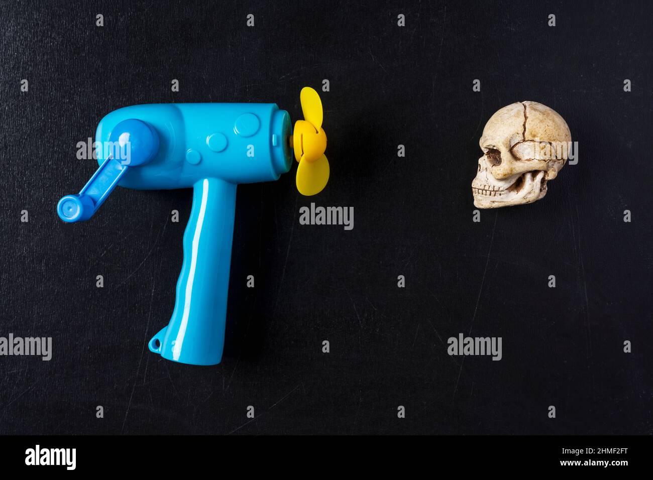 Creative composition a hand-operated toy fan blows on a skull on a ...