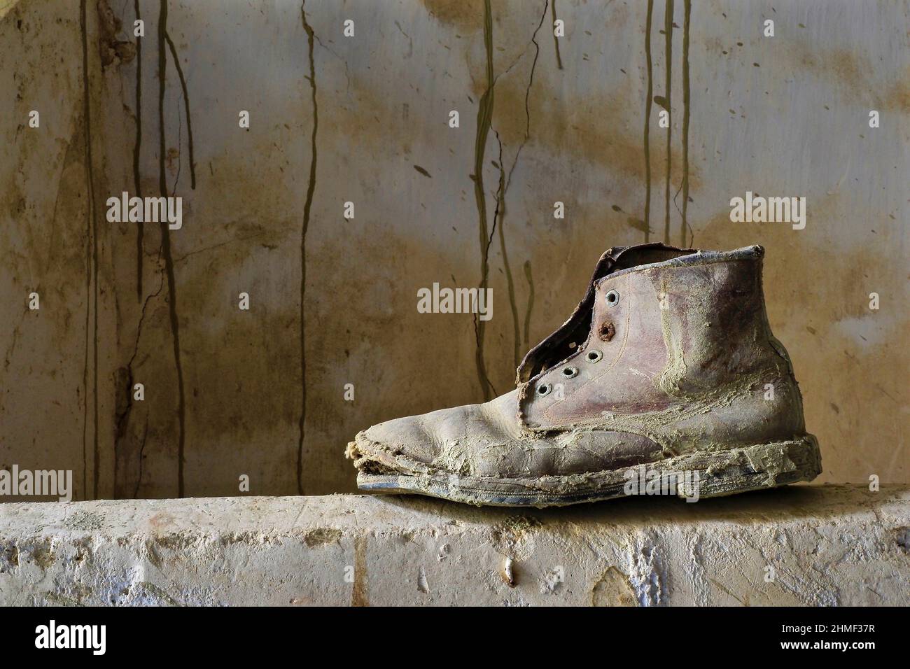 Ailing leather work boot stands on a wall, rotten shoe, shoe wreck ...