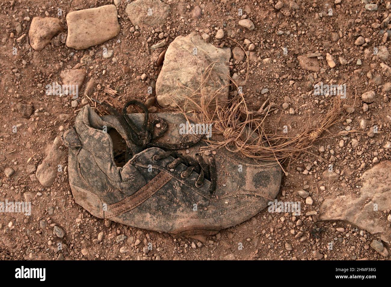 Ailing leather work boot stands on a wall, rotten shoe, shoe wreck ...
