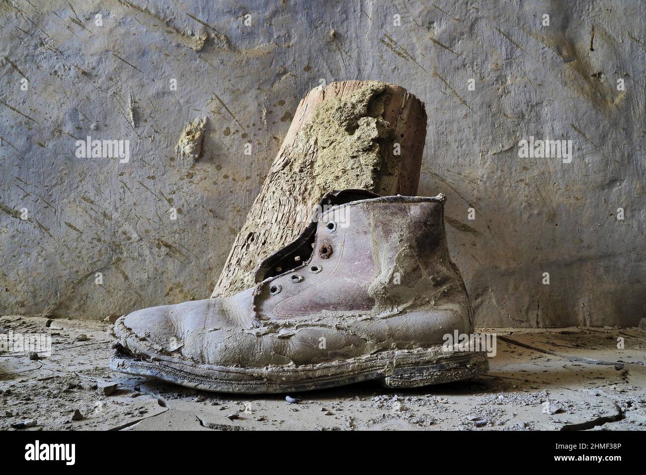 Ailing leather work boot stands on a wall, rotten shoe, shoe wreck ...