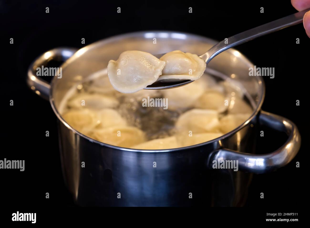 Dumplings mixed with a spoon in a pot of boiling water. Boiled ...
