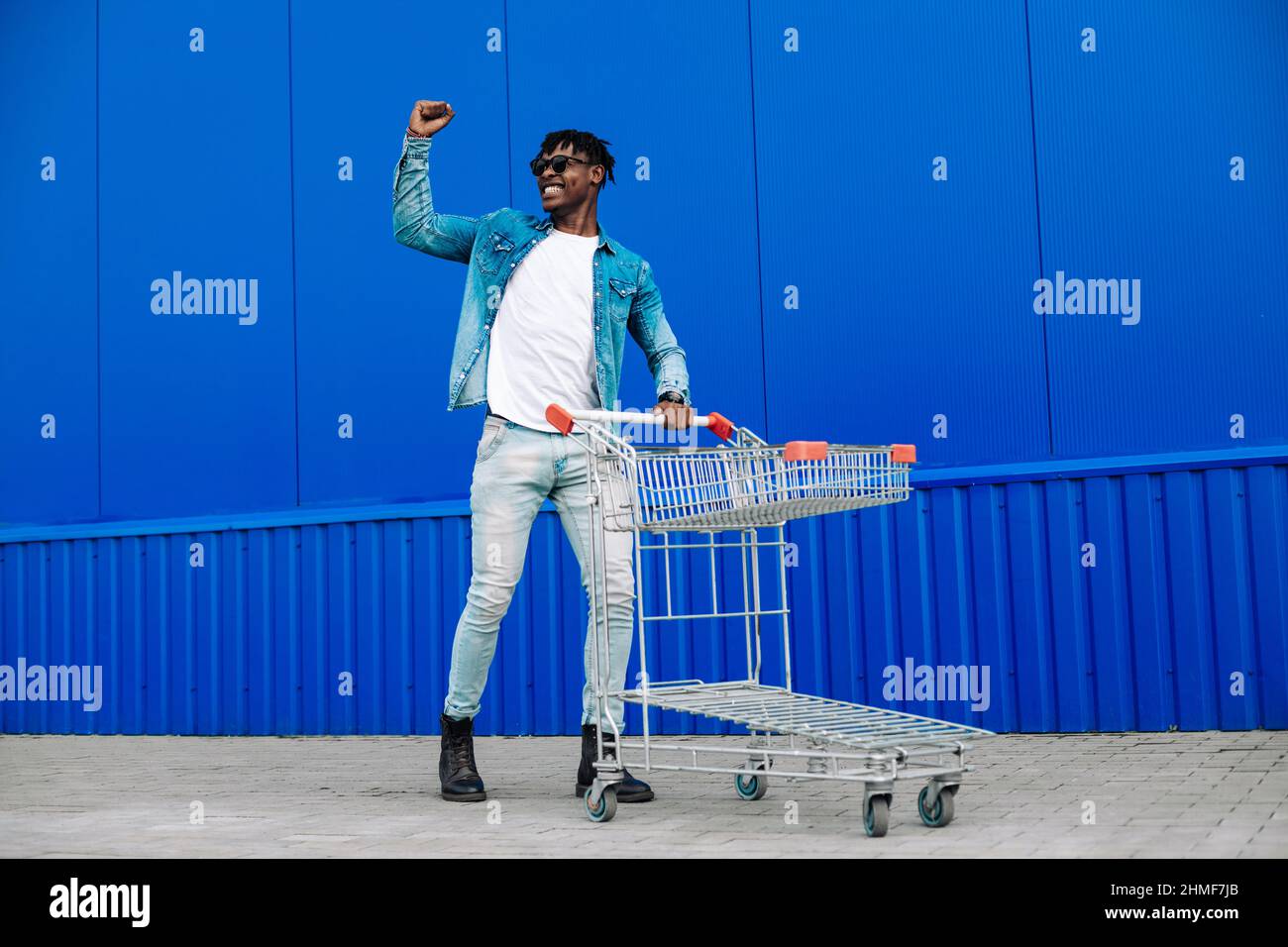 Shopping day. Photo of happy black man with shopping cart celebrating ...