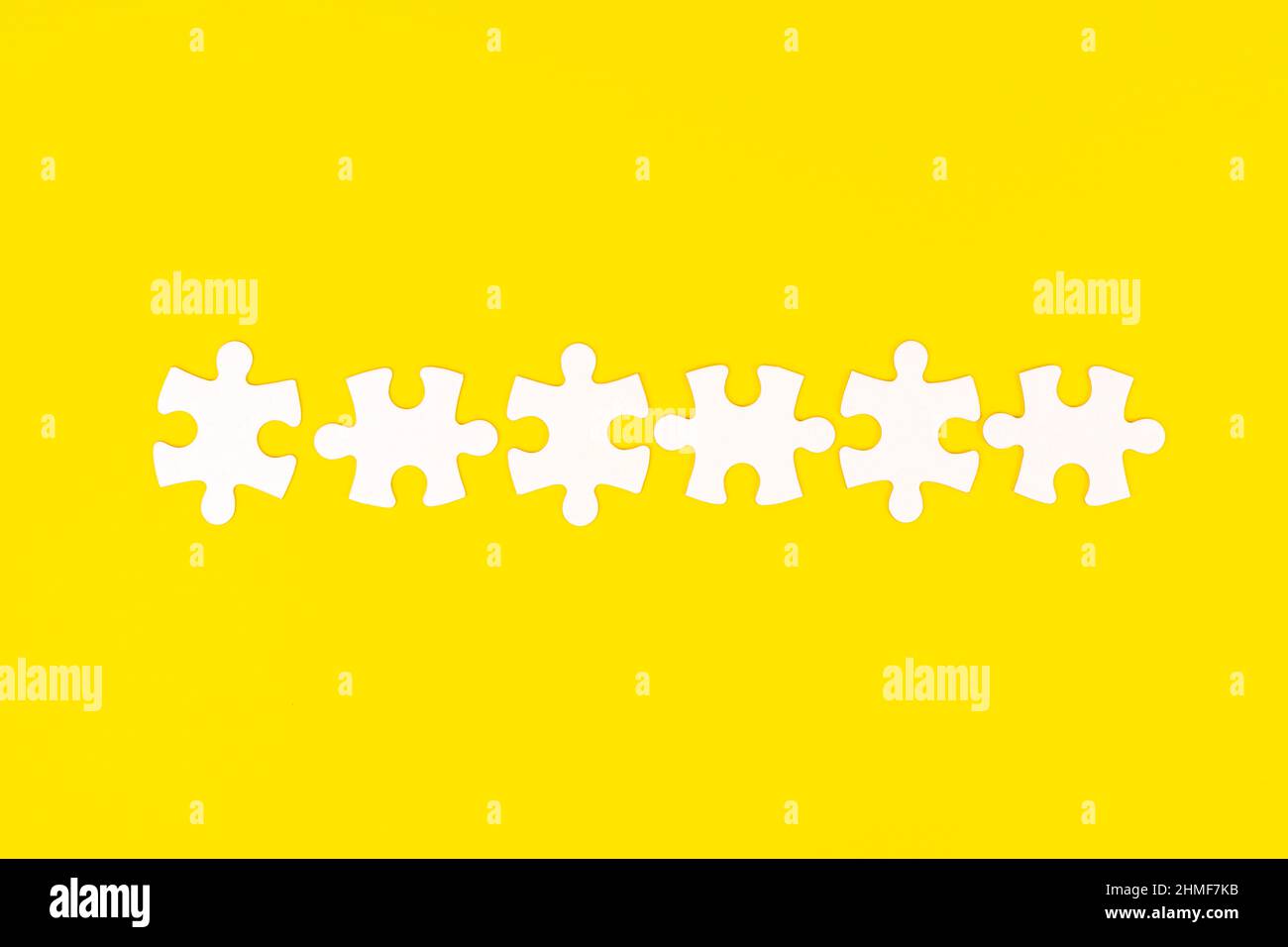 a row of white puzzle pieces on a yellow colored background Stock Photo ...