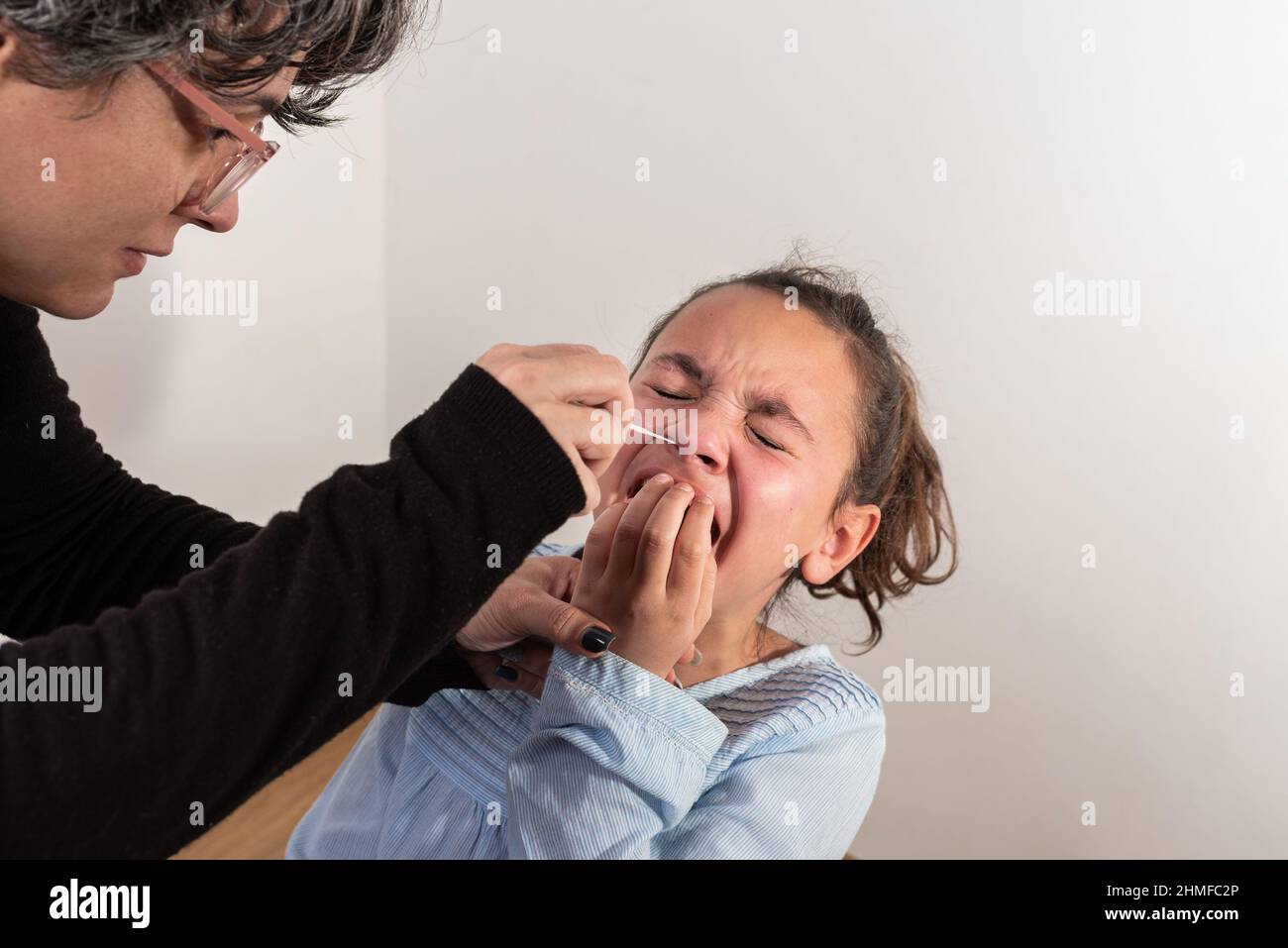 Little girl crying while her mother performs her a rapid covid-19 test ...