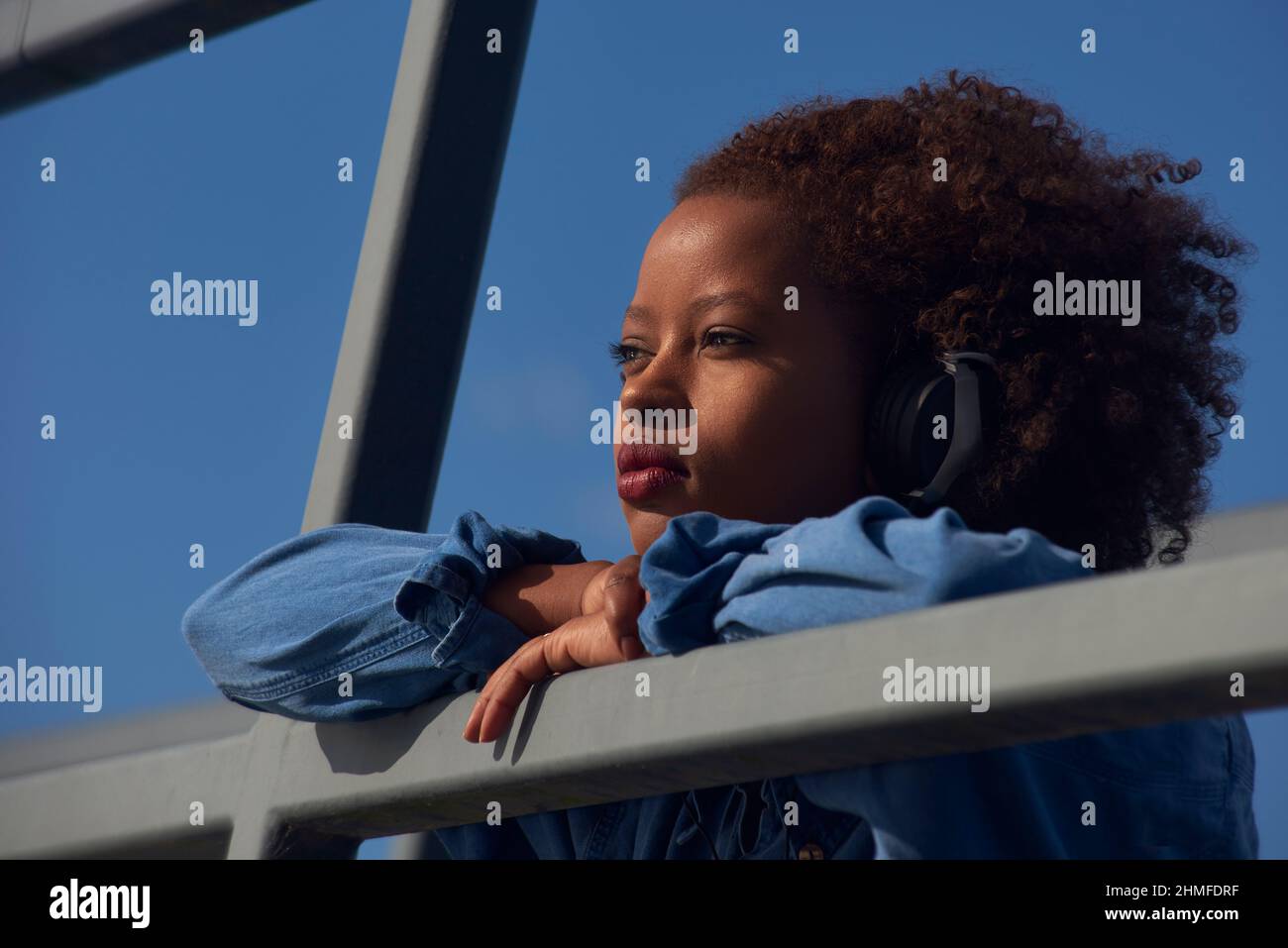 Portrait of a young black female with big afro hair wearing headphones ...