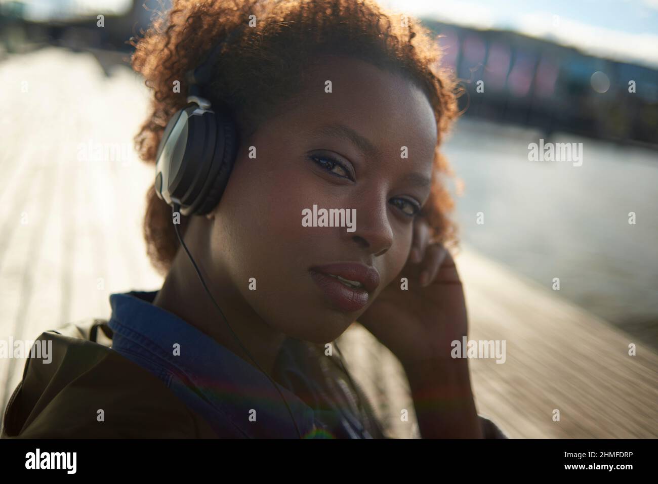 Portrait of a young black female with big afro hair wearing headphones ...