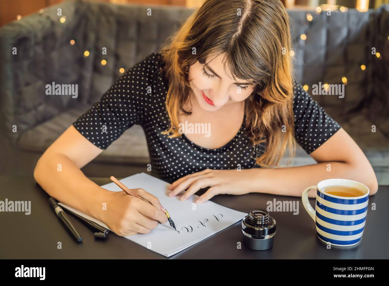 Calligrapher Young Woman writes phrase on white paper. Inscribing ...