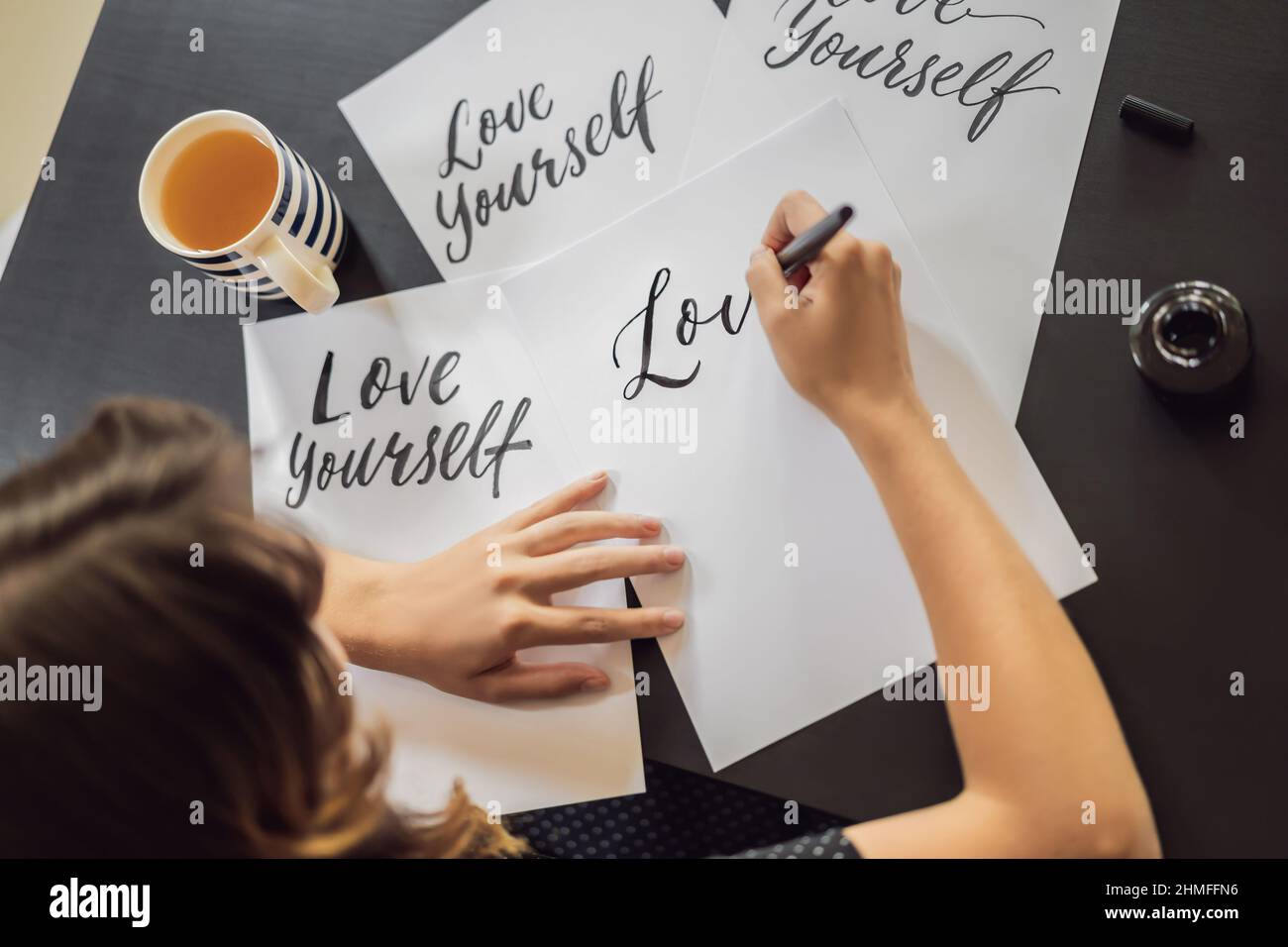 Love yourself. Calligrapher Young Woman writes phrase on white paper ...