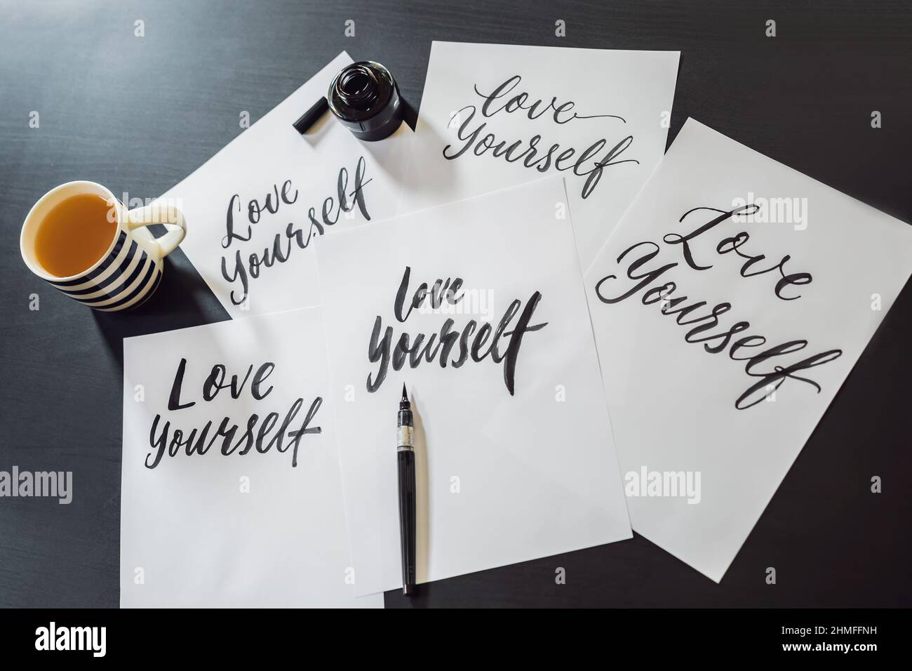Love yourself. Calligrapher Young Woman writes phrase on white paper ...