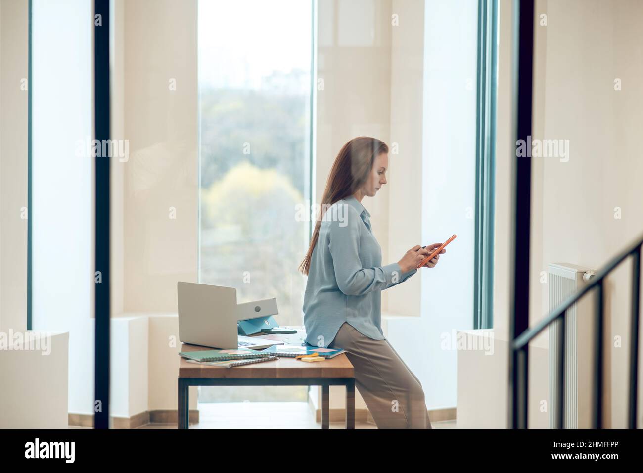 Woman sideways to camera looking at tablet Stock Photo - Alamy