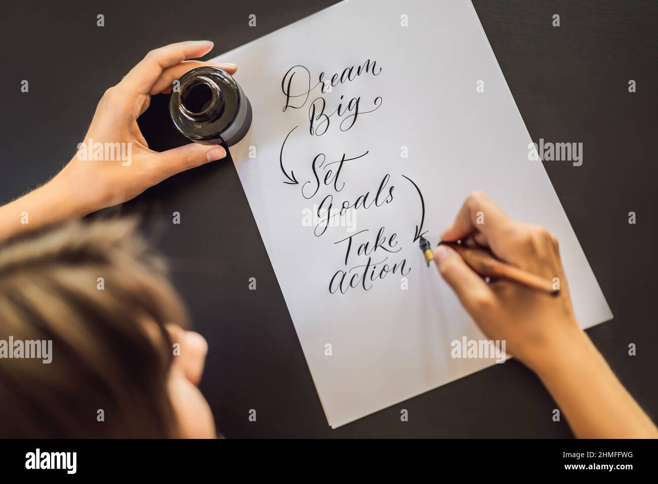 dream big set goals take action. Calligrapher Young Woman writes phrase ...