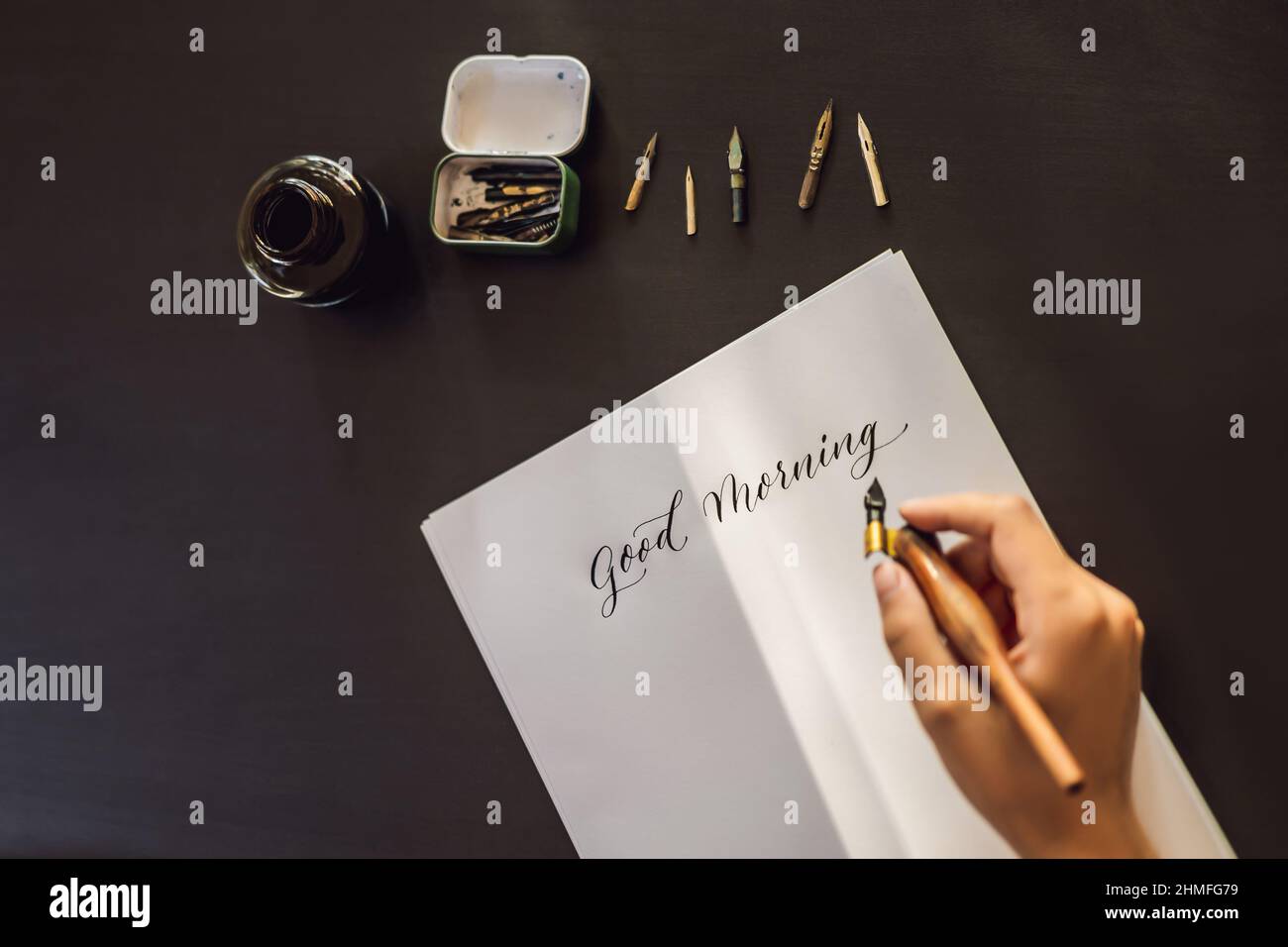 Good morning. Calligrapher Young Woman writes phrase on white paper ...