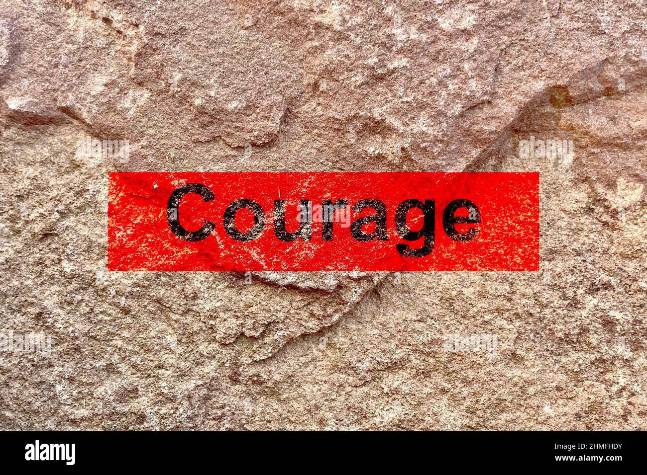 Closeup of an abstract design of Courage written on weathered stone wall background Stock Photo ...