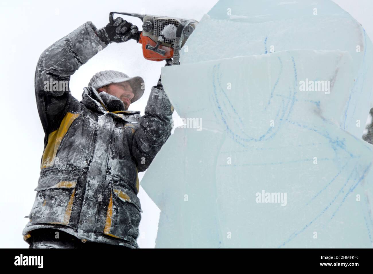 The sculptor cuts ice contours from ice with a chainsaw for Christmas ...
