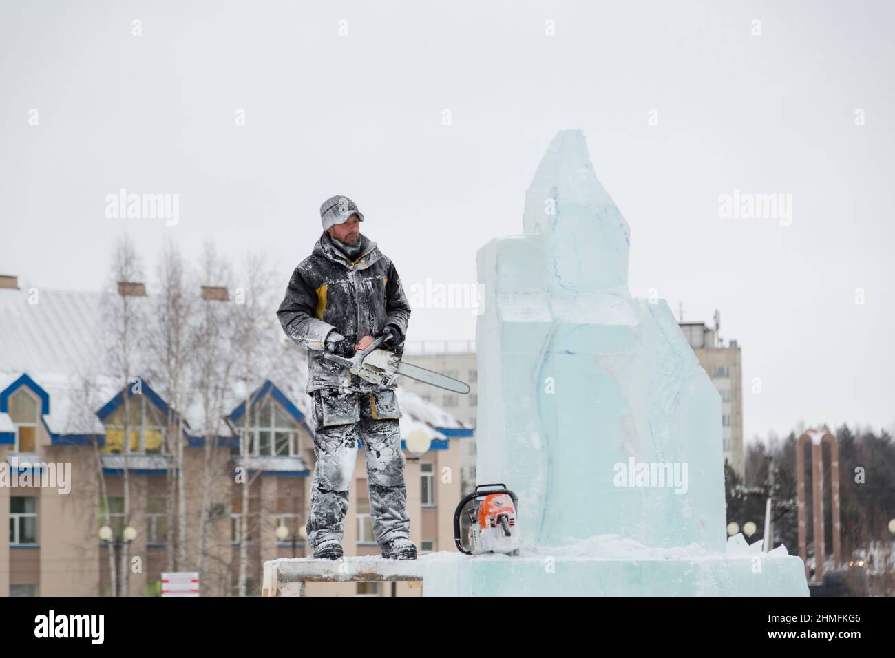 Sculptor on the scaffolding with a chainsaw next to a stalking figure ...