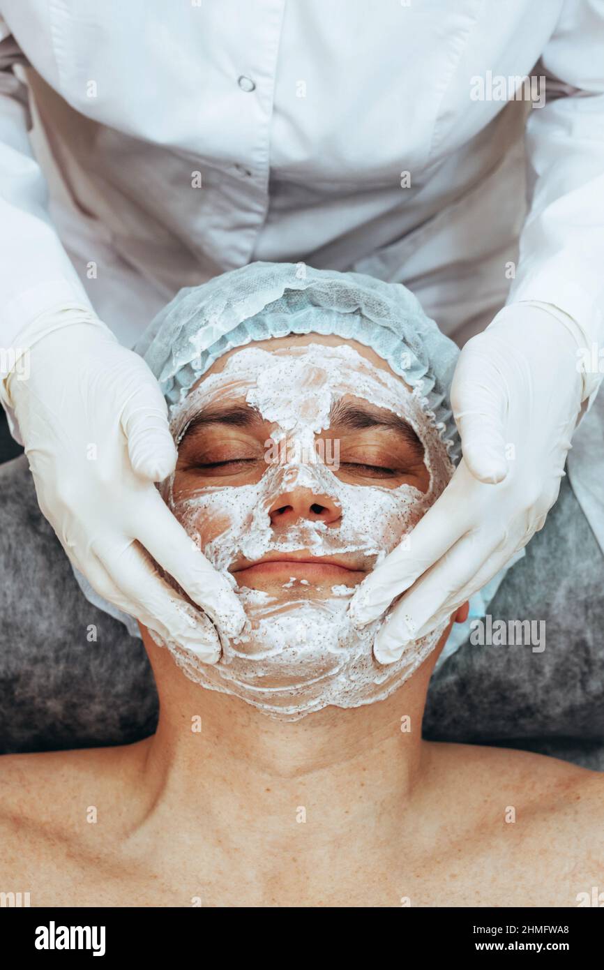 Beautician applying scrub mask on face to young man, spa beauty salon ...
