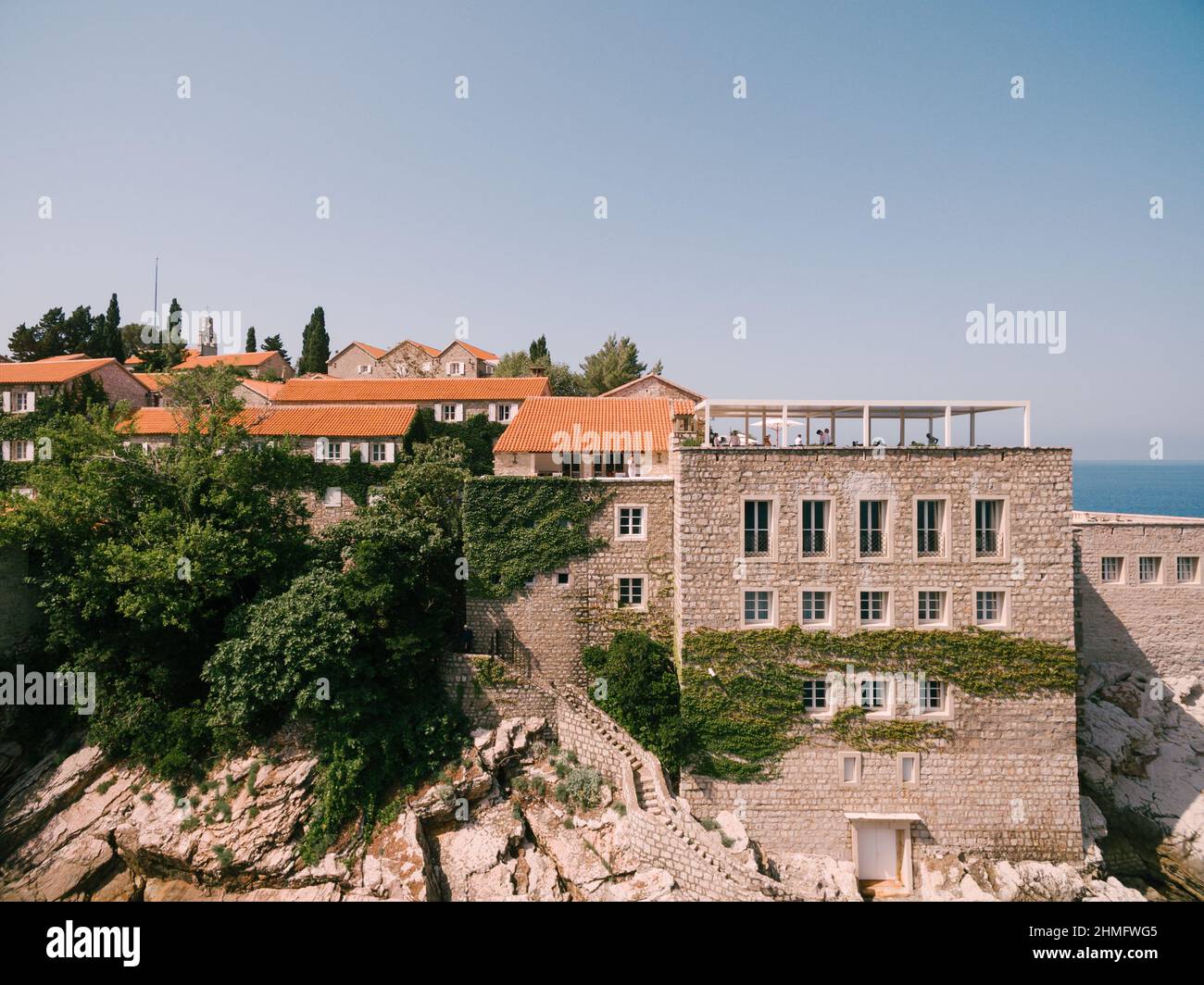 Ancient stone building entwined with ivy on the island of Sveti Stefan ...