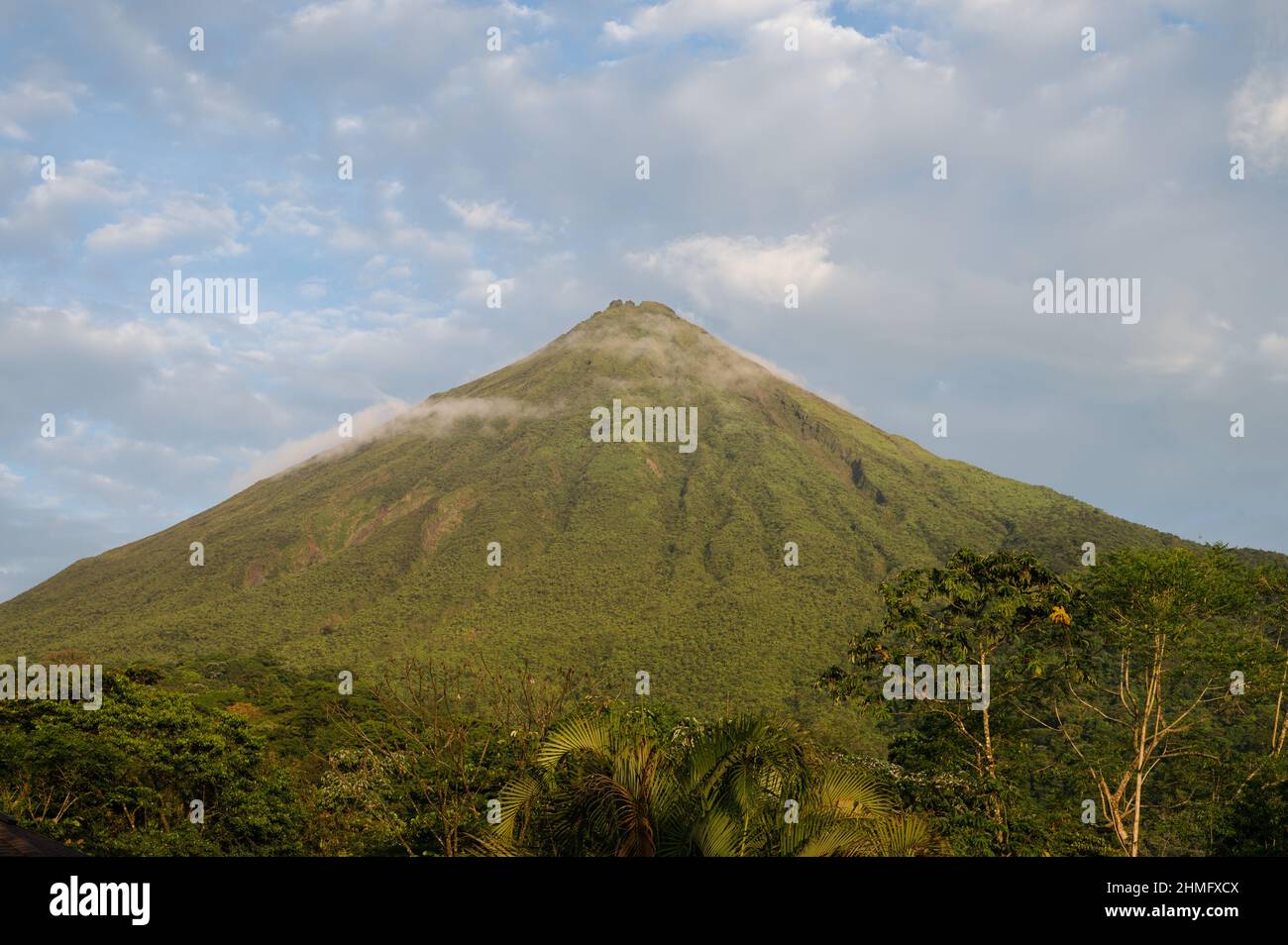 Horizontal shot of full view of green Arenal Volcano with hovering ...