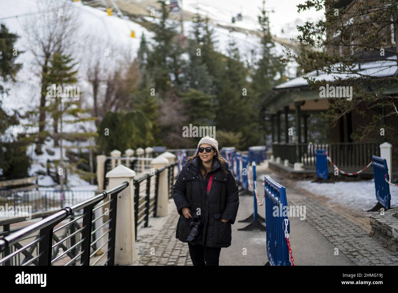Caucasian woman walking on a path next to a barrier in cold weather ...