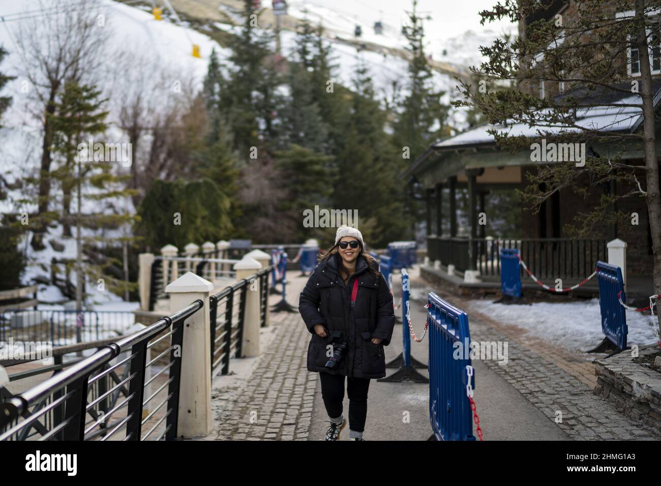 Caucasian woman walking on a path next to a barrier in cold weather ...
