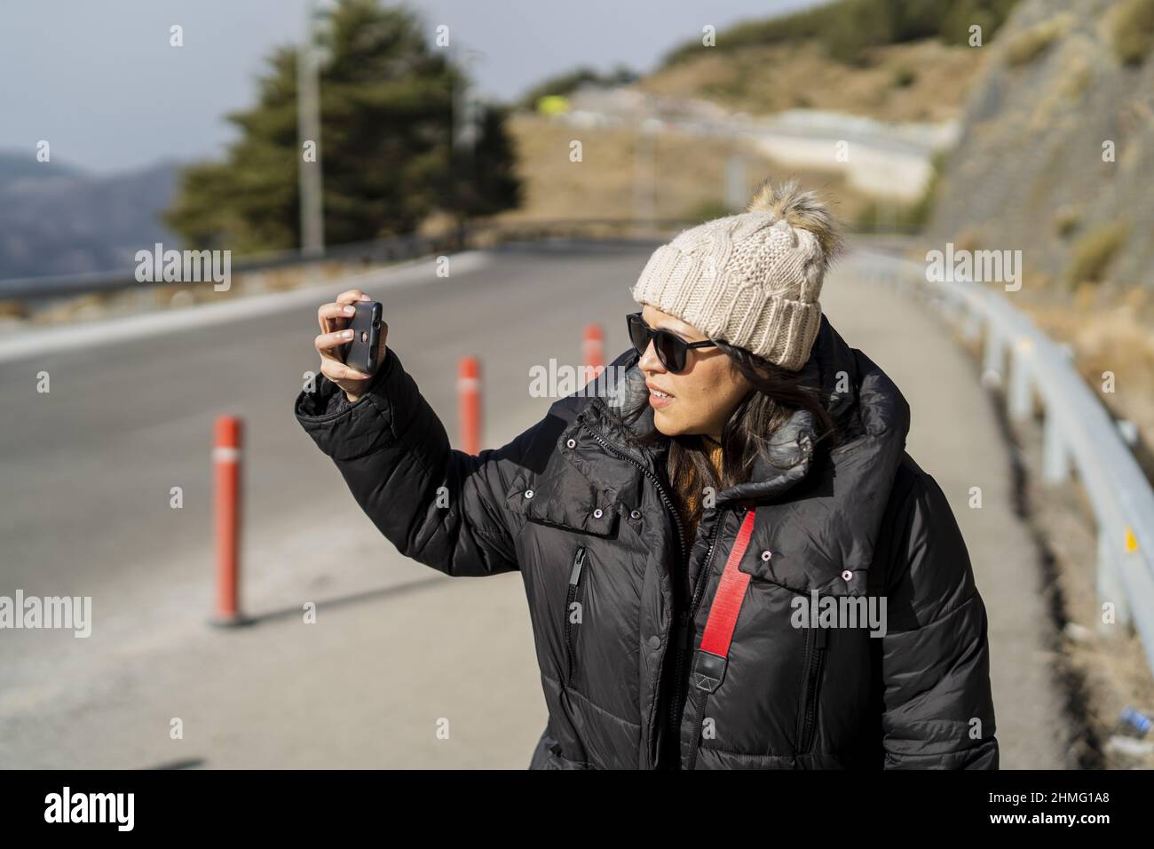 Shot of a Caucasian woman walking on a roadside and taking some ...