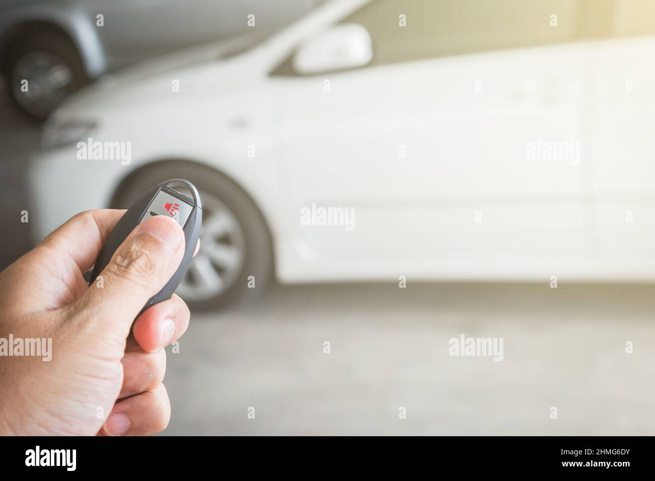Hand holding button on the remote car at car park background Stock ...