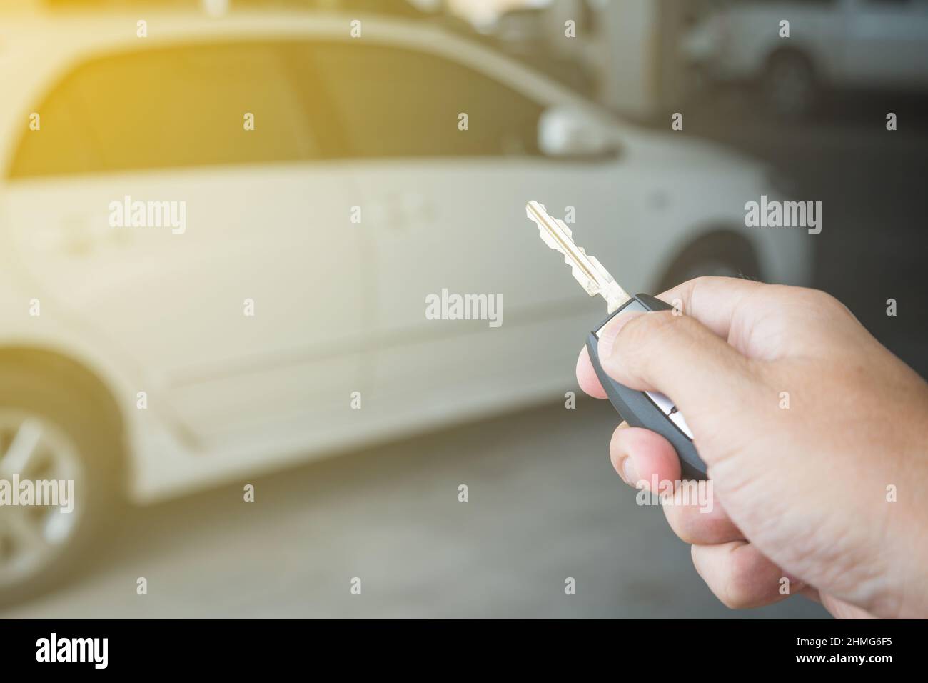 Hand holding button on the remote car at car park background Stock ...