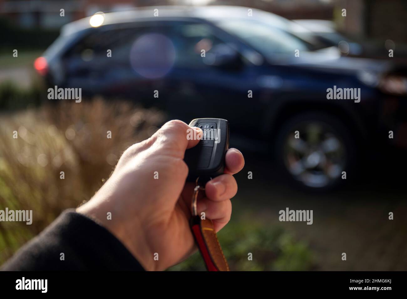 A close up portrait of a person holding a car key in his hand pressing ...