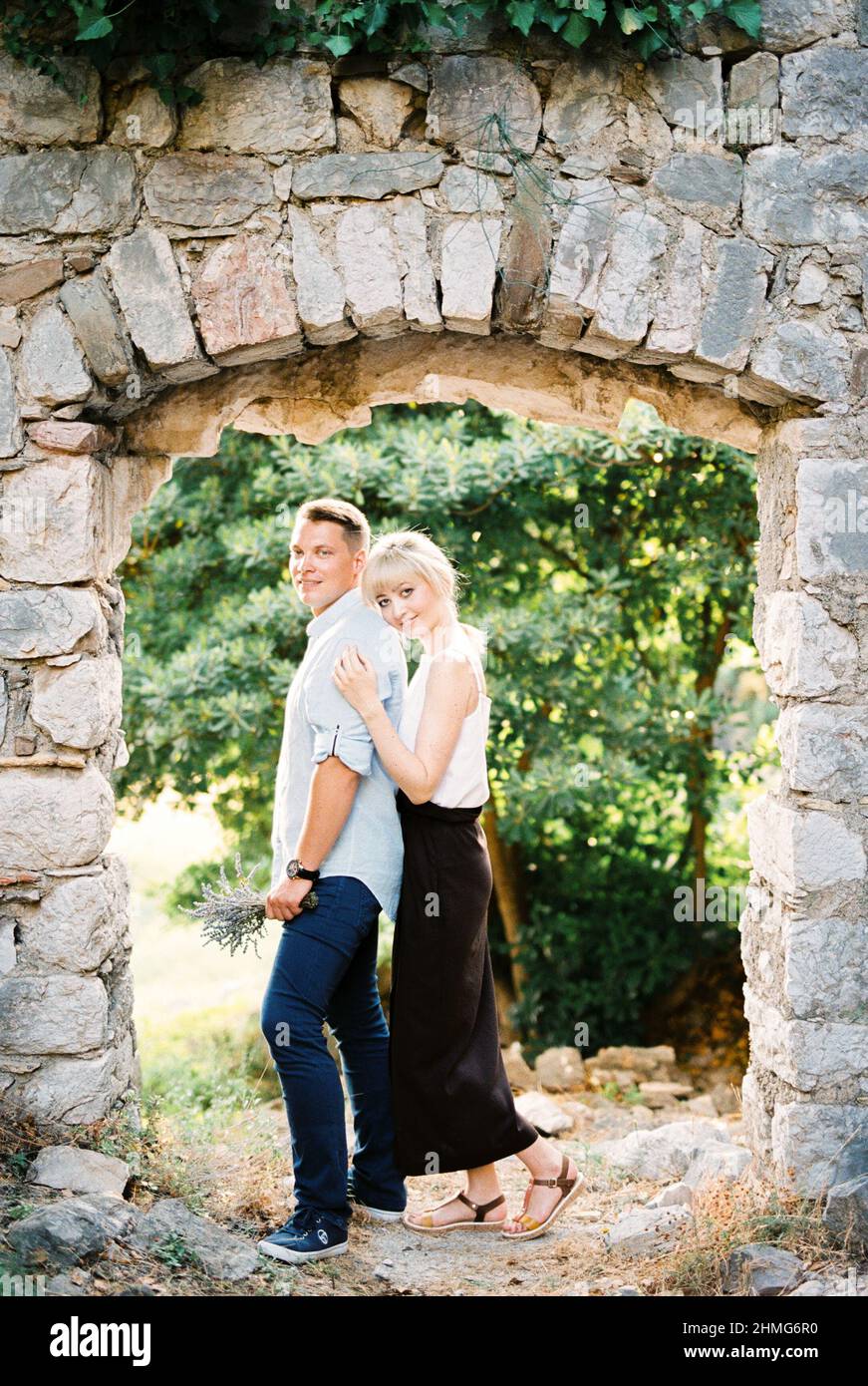 Woman hugs from behind a man near a stone wall of an old castle Stock ...