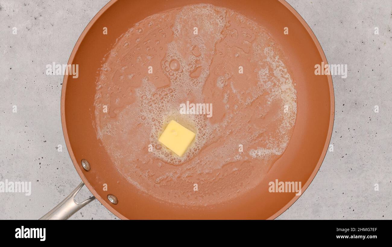 Hot frying pan with melting butter close up on light grey background ...