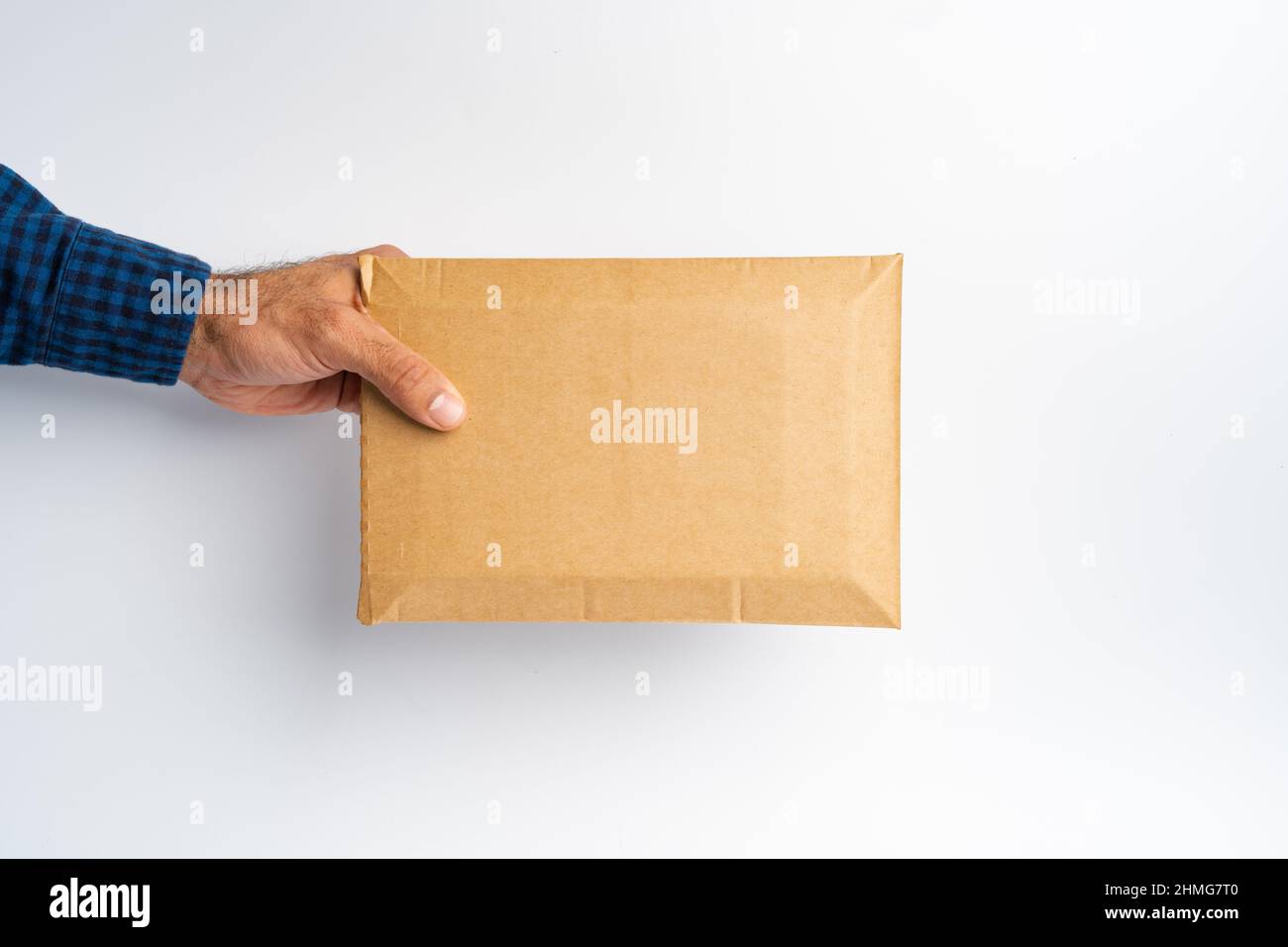 Male hand holding parcel post against white background Stock Photo - Alamy