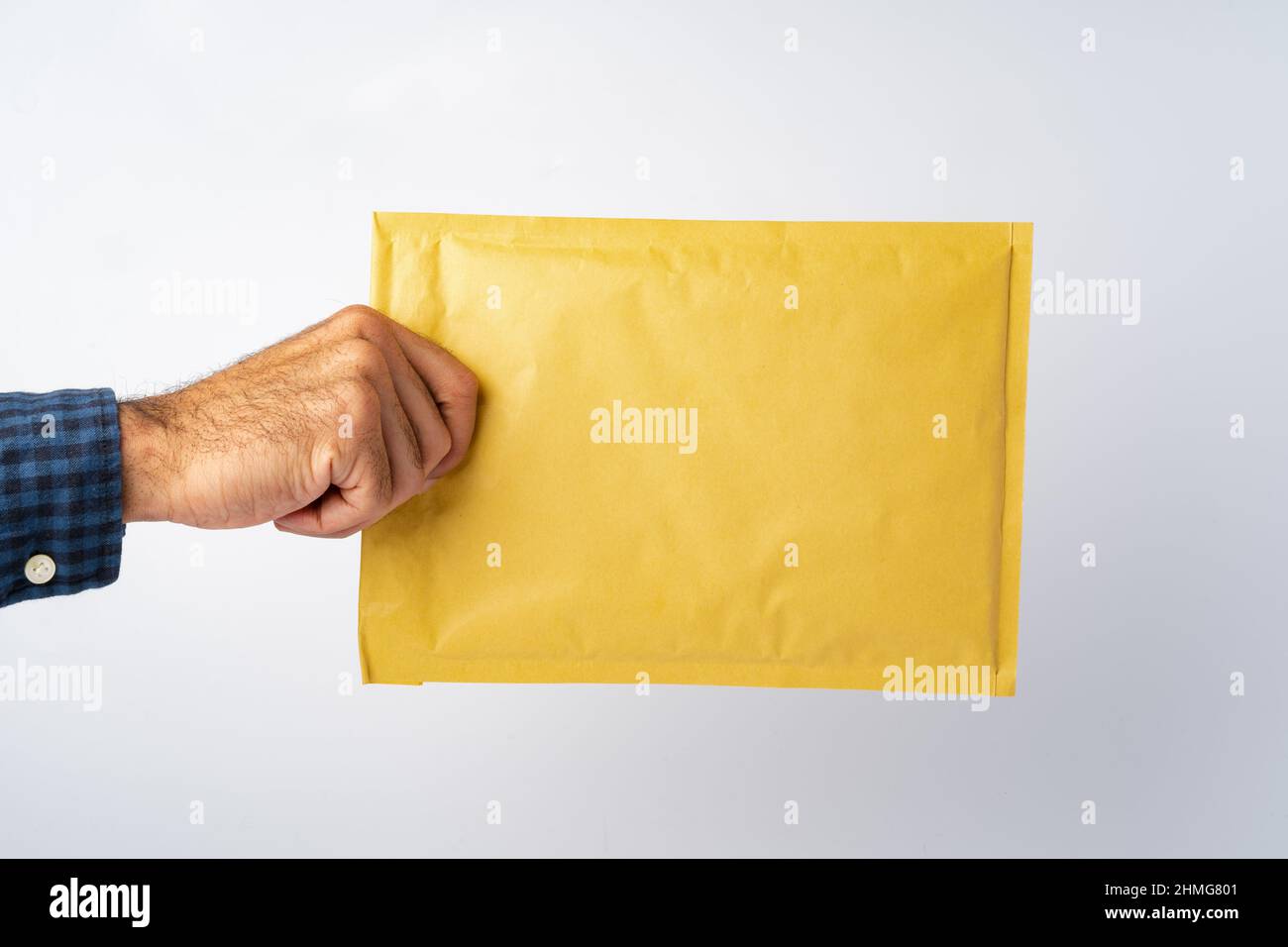 Male hand holding parcel post against white background Stock Photo - Alamy