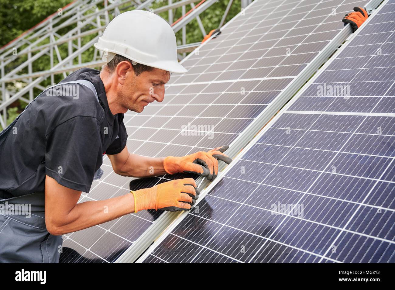 Side view of man solar installer building photovoltaic solar panel ...