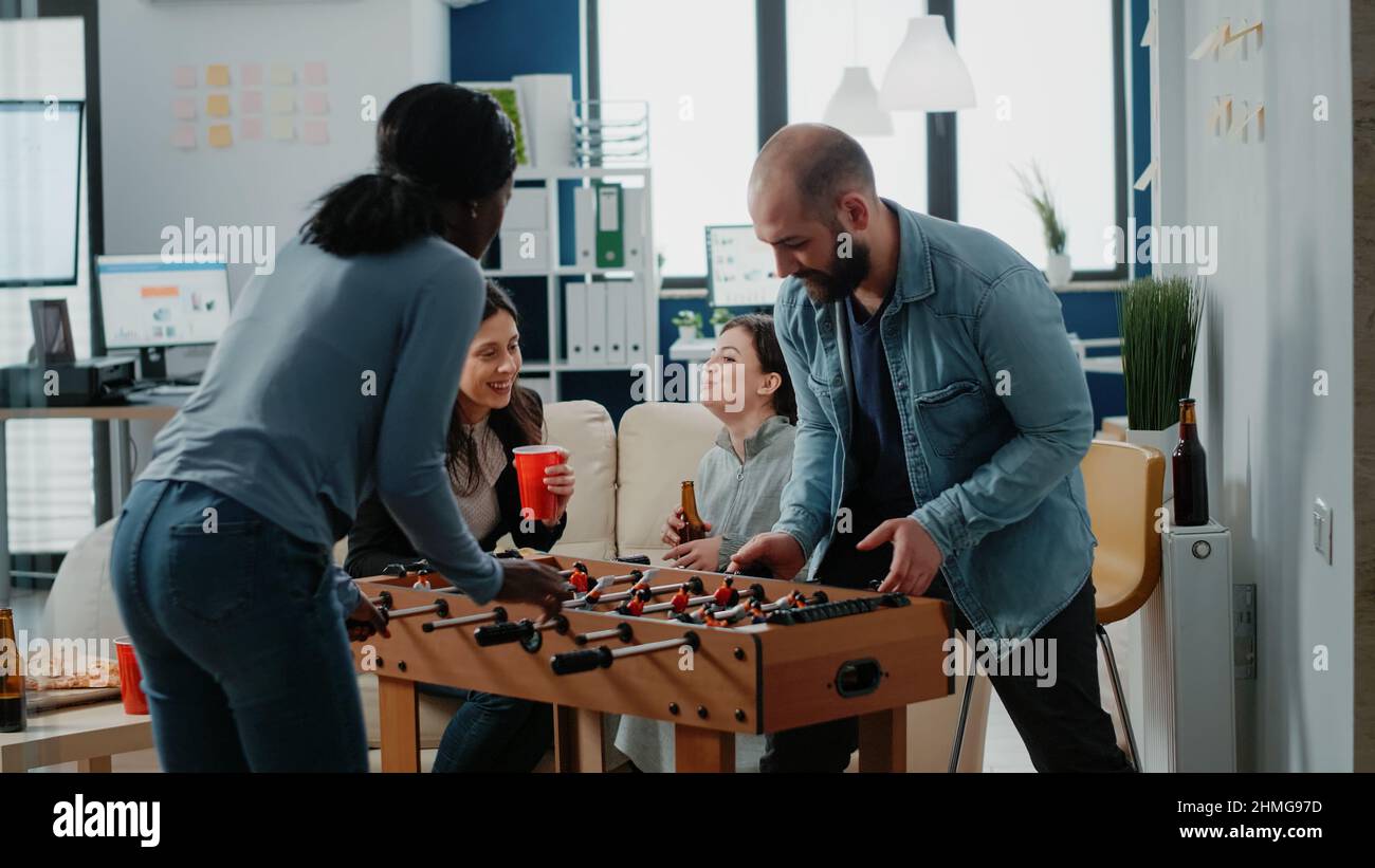 Diverse group of workmates enjoying game with foosball table to do fun ...