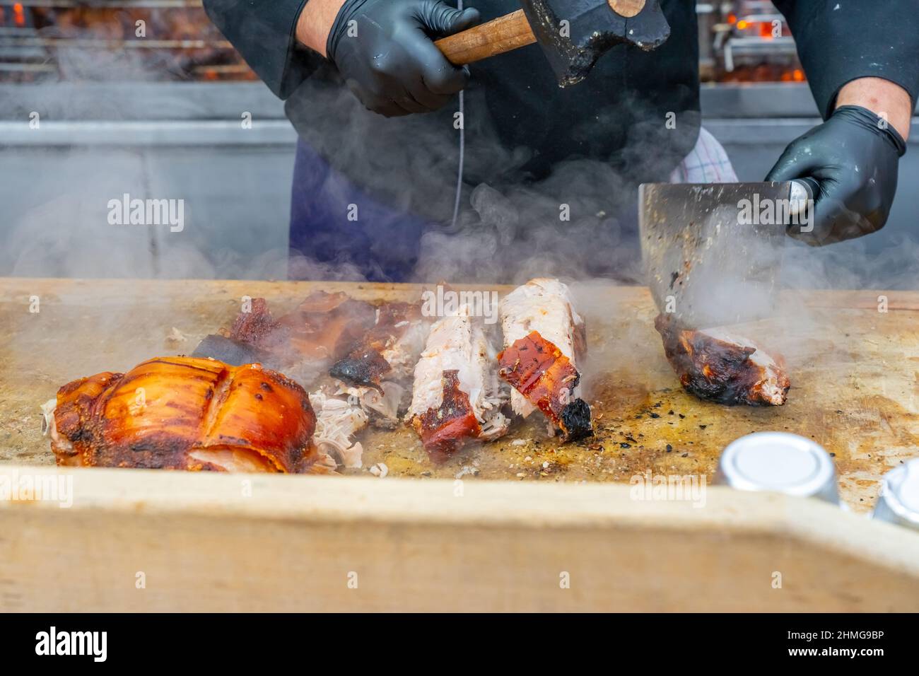 Street grill, fried meat. A man cuts a fried piece of meat into portion ...