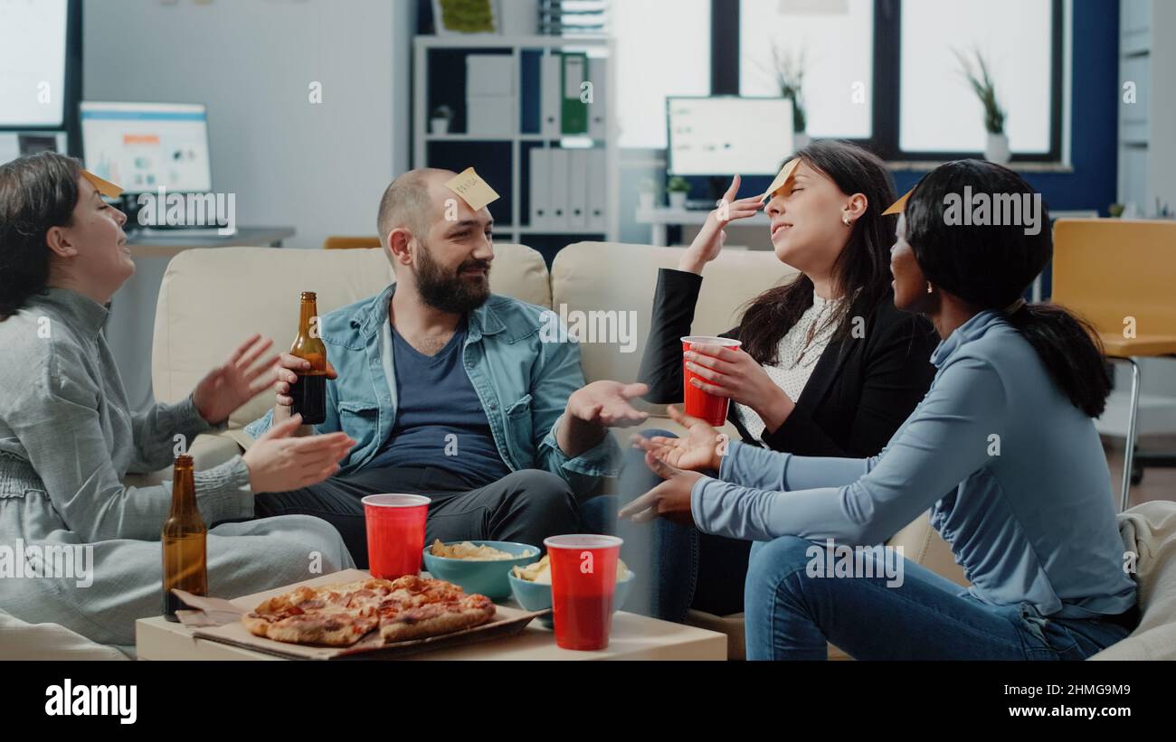 Diverse group of workmates playing charades with sticky notes on ...