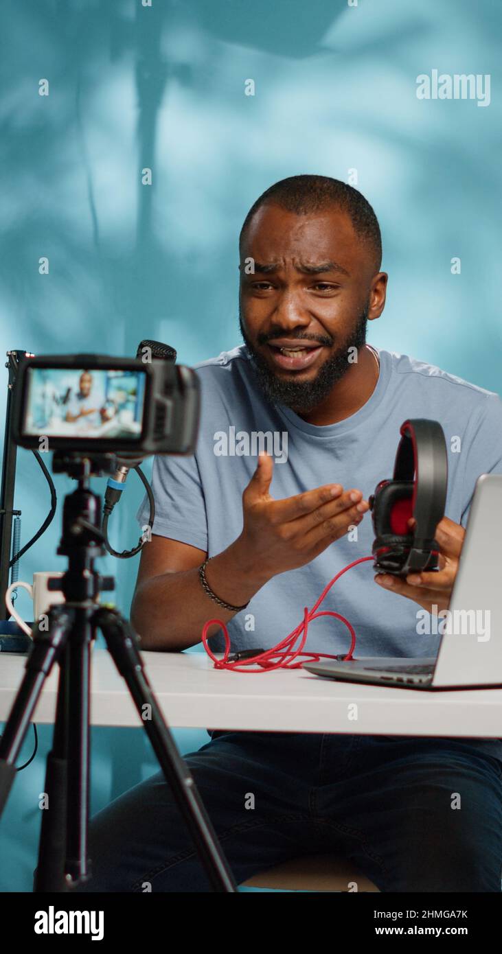 Content creator holding headphones for product review on camera with ...