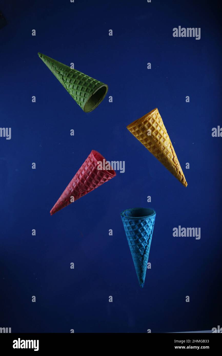 four waffle cones of different colours levitating against blue ...
