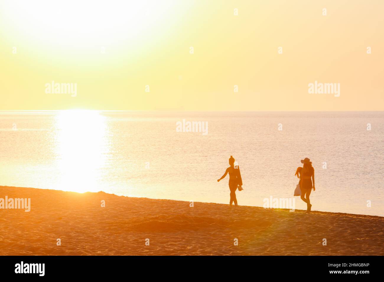 group of friends walking by sandy beach on sunset. summer vacation ...