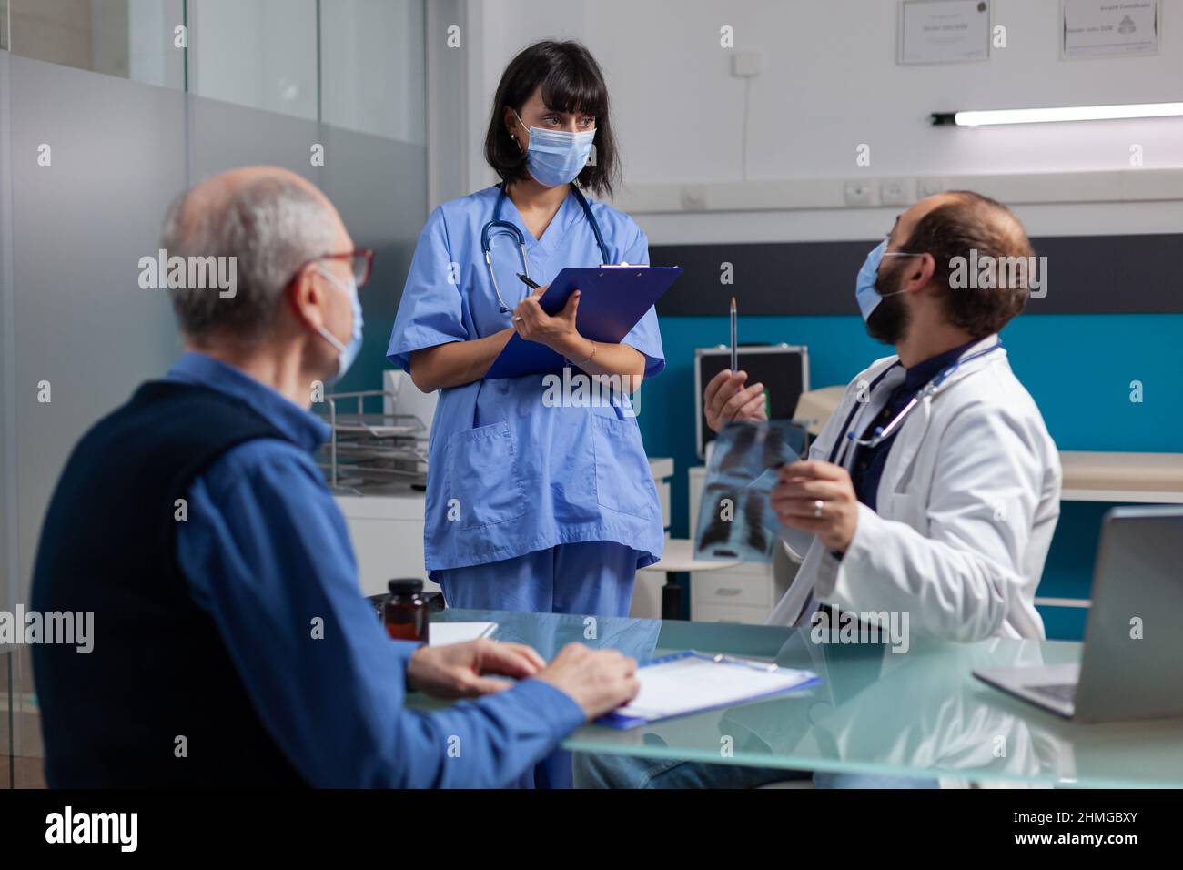 Physician talking to nurse and holding x ray scan at checkup visit with ...